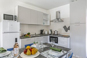 Cozinha moderna com armários brancos, micro-ondas embutido e fogão a gás.