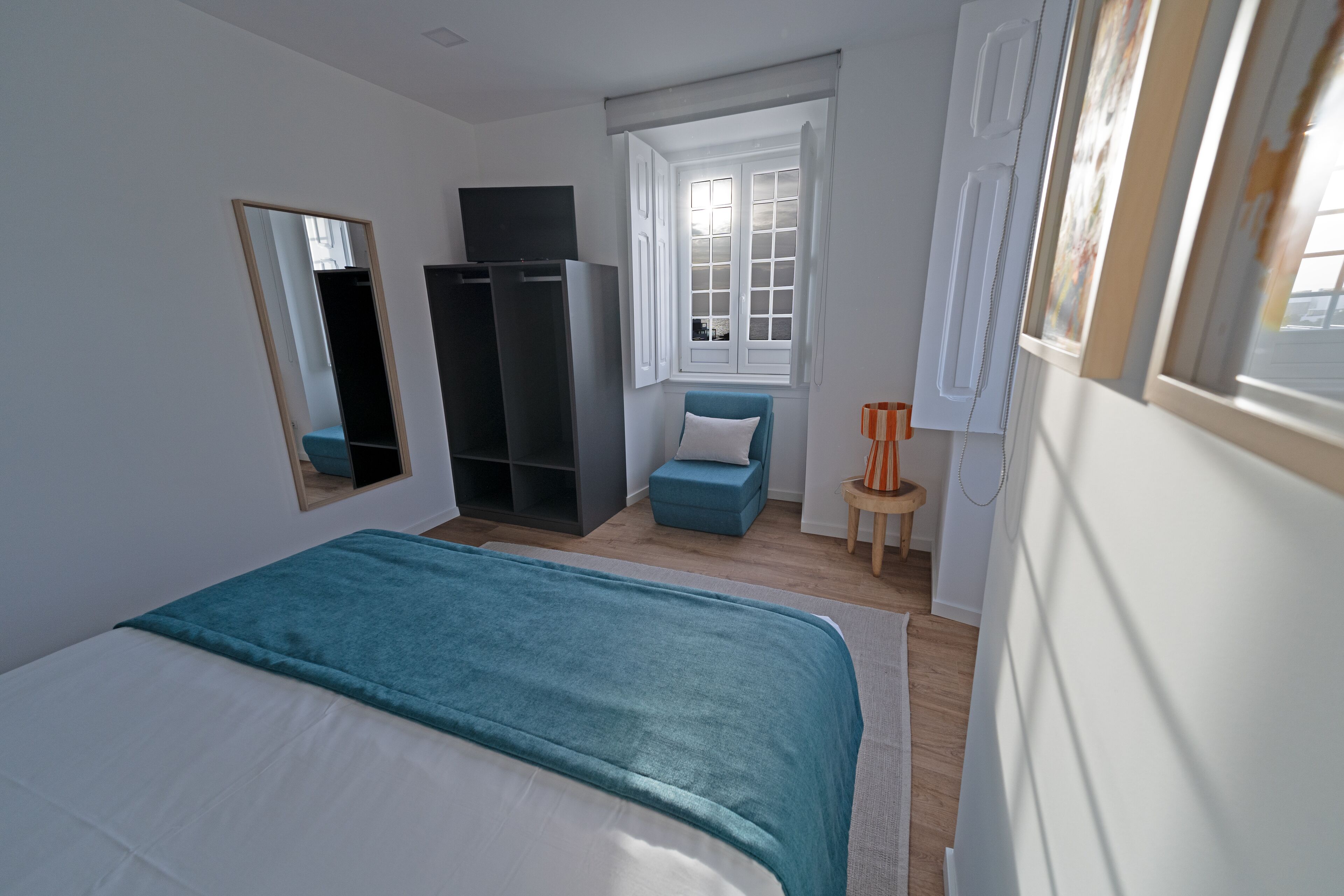 Quarto com cama, guarda-roupa, escrivaninha e janela.