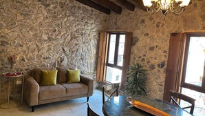 Um quarto com paredes de pedra, um sofá, uma mesa e um candelabro.