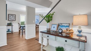 Uma sala de estar moderna com escada, área de jantar e cozinha visível ao fundo.