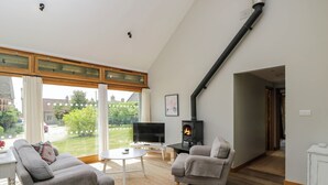 Uma sala de estar com lareira, televisão e vista para o jardim.