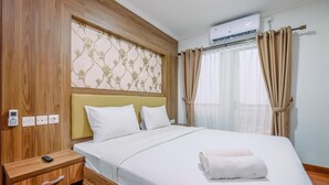 Quarto de hotel com cabeceira de madeira, cama com roupa de cama branca, mesa de cabeceira com controle remoto e janela com cortinas bege.
