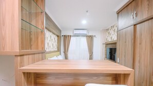 Quarto com mesa de jantar de madeira, duas cadeiras brancas, prateleira de vidro e ar condicionado fixado na parede.