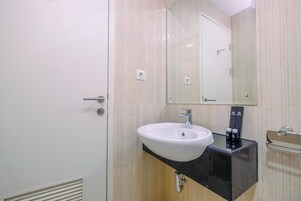 Casa de banho moderna com lavatório branco, bancada preta e um espelho grande.