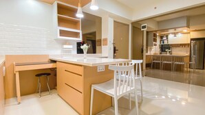 Cozinha moderna com ilha central, cadeiras brancas e iluminação pendente.