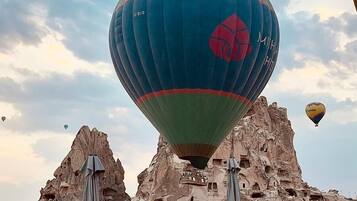 Um balão de ar quente com um logotipo, com formações rochosas e um céu claro ao fundo.