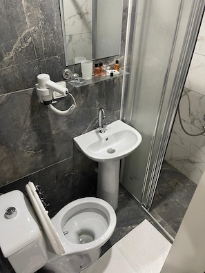 Quarto triplo básico, vista para o pátio | Banheiro | Chuveiro, secador de cabelo, toalhas de banho, sabonete