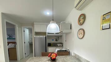 Uma cozinha com geladeira, luminária pendente e ar-condicionado fixado na parede.