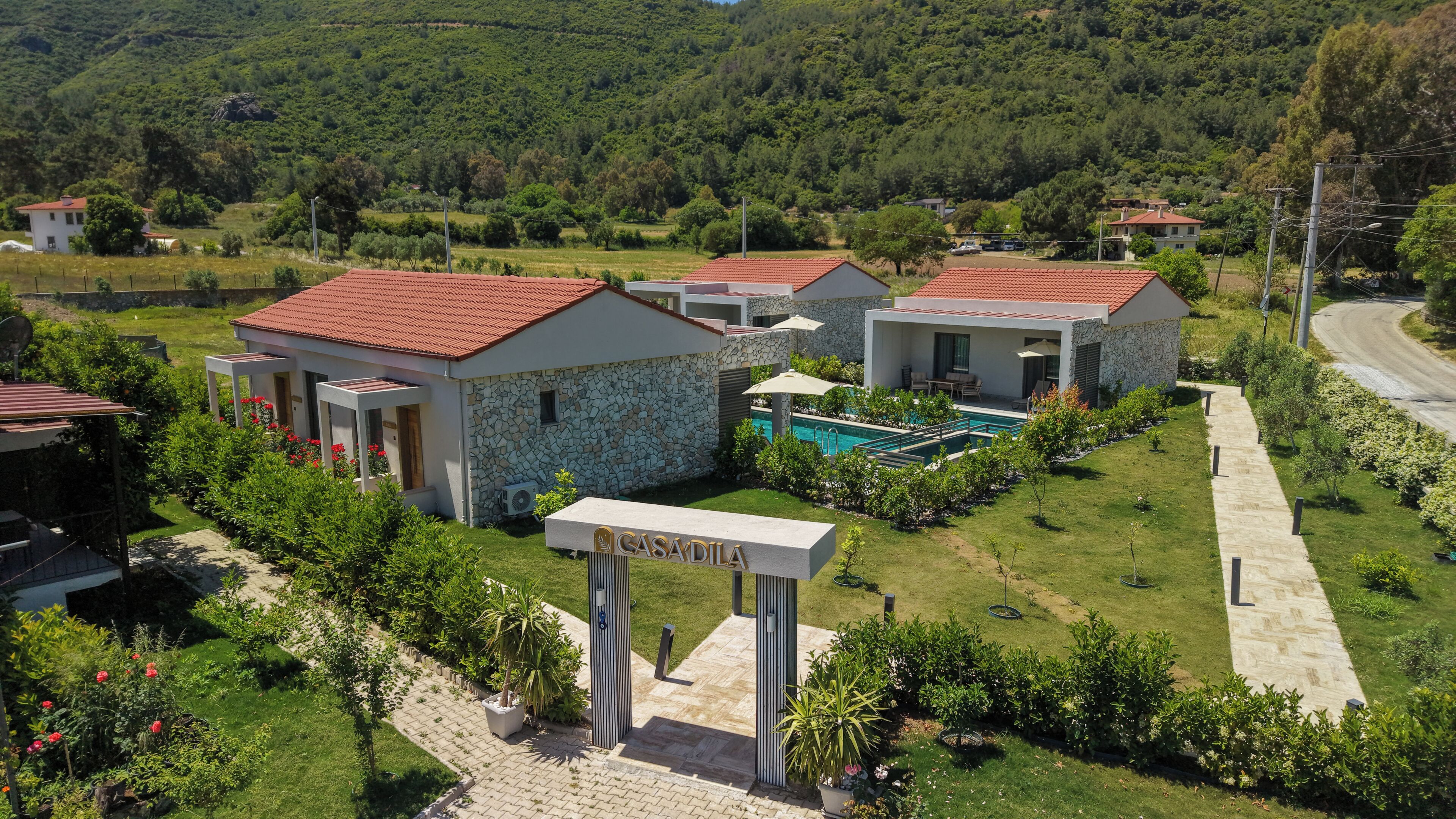 Área residencial com casas revestidas de pedra, piscina e uma placa com a inscrição 'CASADILA'.
