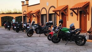 Um edifício com torre, quartos numerados e motocicletas estacionadas.