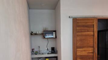 Uma cozinha compacta equipada com forno embutido, pia pequena e máquina de café.