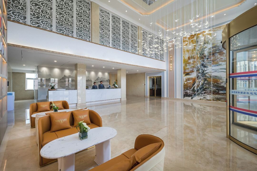 Um hall amplo com balcão de recepção, área de estar e um grande mural.