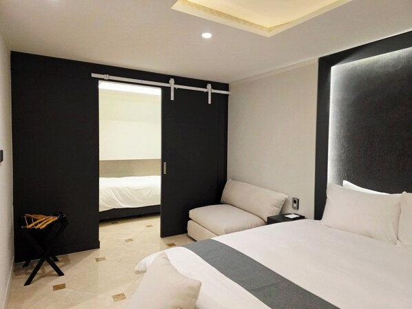 Quarto moderno com uma cama grande, um sofá, uma escrivaninha e uma porta de correr para uma varanda.