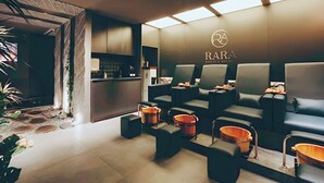 Uma área de spa com assentos, um balcão de recepção e um logotipo na parede.