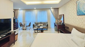 Quarto de hotel com uma cama, televisão, sofá, mesinha e secretária.