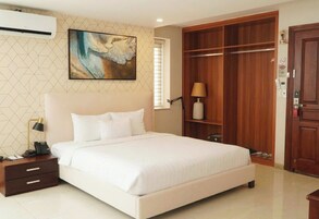 Um quarto com cama, luminária de cabeceira, mesa de cabeceira e um guarda-roupa de madeira.