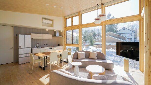 Interior moderno com cozinha, sala de jantar e área de estar, com amplas janelas e vista para uma paisagem nevada.