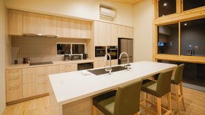 Uma cozinha moderna com armários de madeira, uma ilha central com banquetas e eletrodomésticos embutidos, além de uma janela ampla.