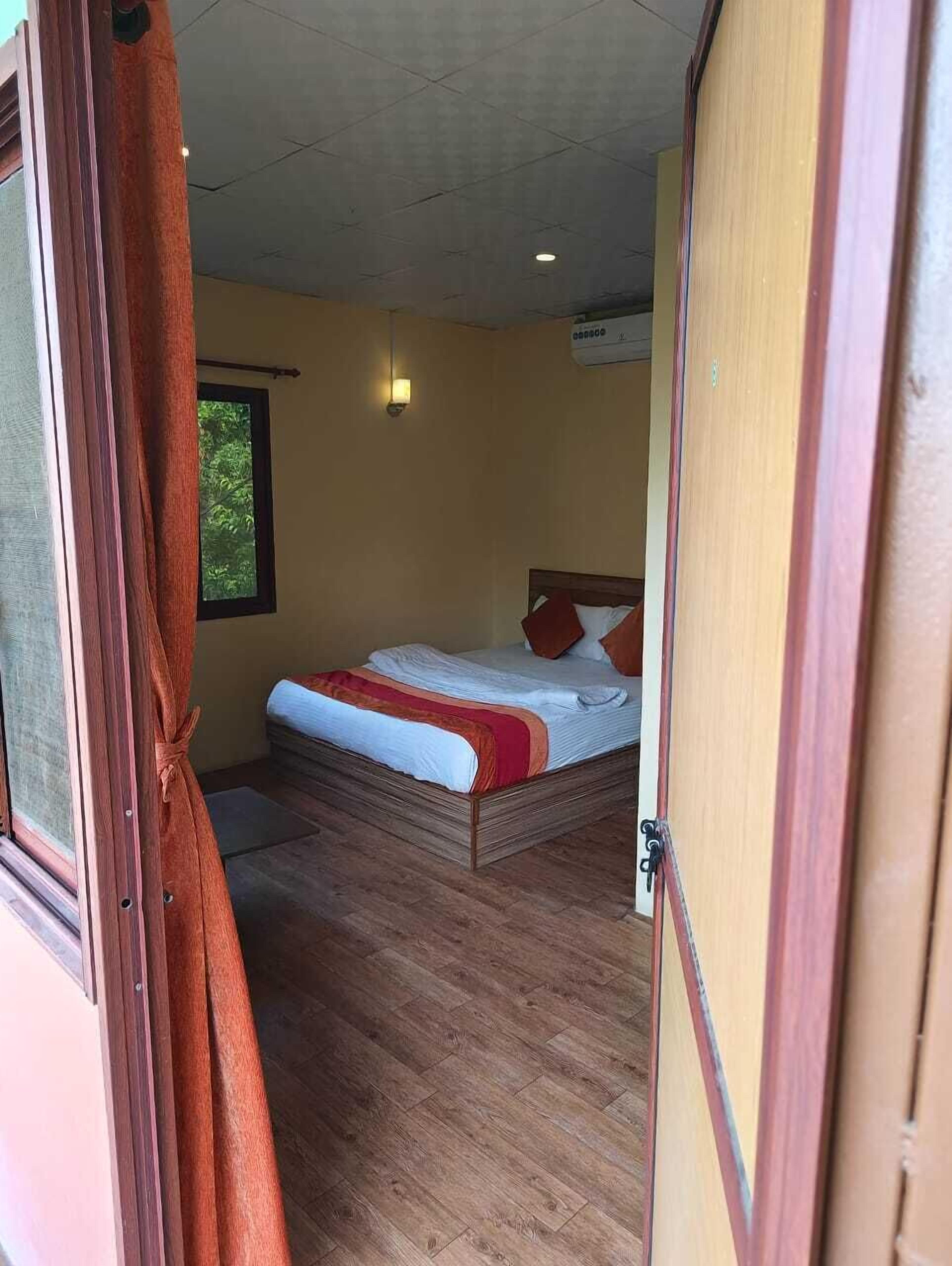 Quarto com cama de madeira, janela e ventoinha no teto.