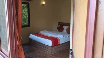 Quarto com cama de madeira, janela e ventoinha no teto.