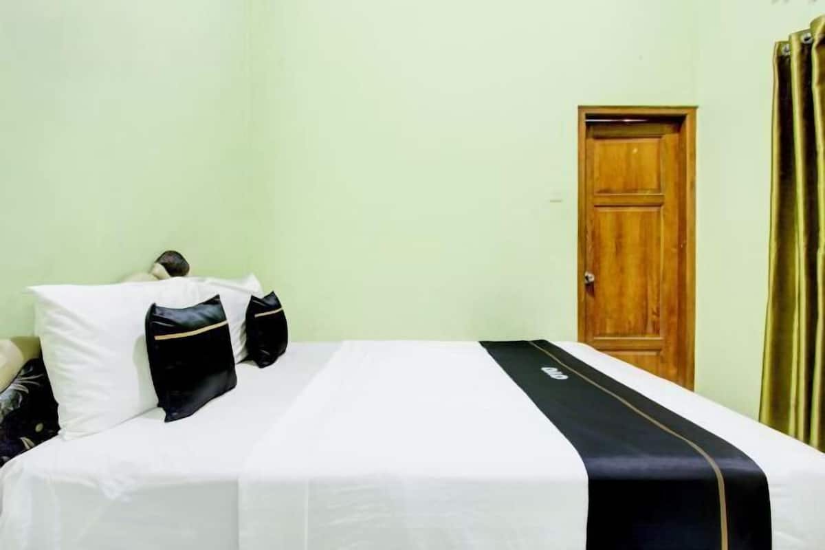 Quarto de hotel com uma cama, uma porta de madeira e uma cortina.