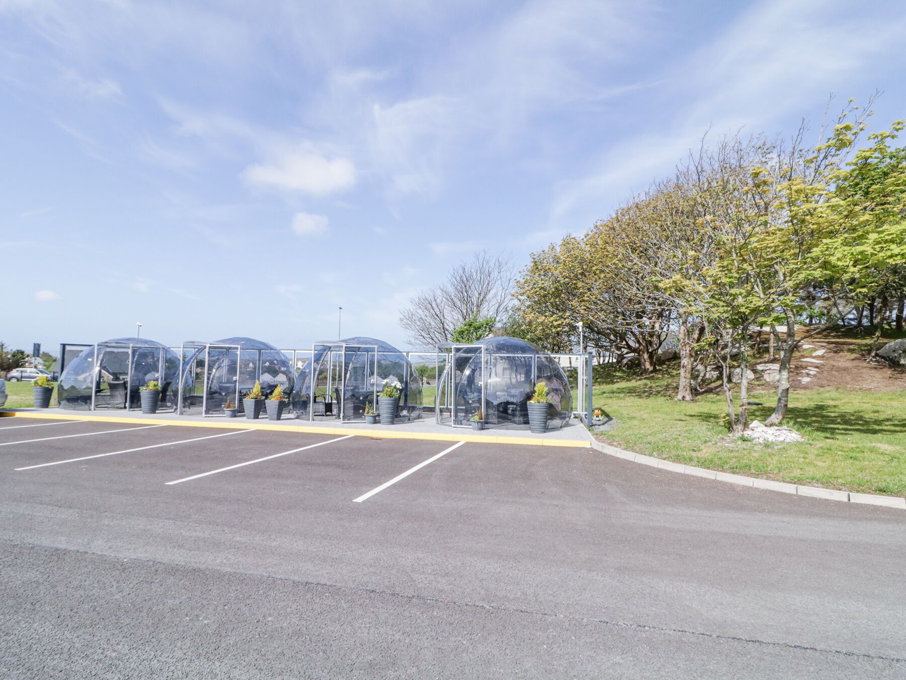 Um parque de estacionamento com estruturas transparentes e em forma de cúpula, possivelmente para abrigo ou proteção.