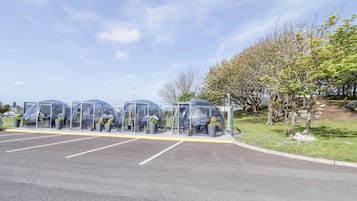 Um parque de estacionamento com estruturas transparentes e em forma de cúpula, possivelmente para abrigo ou proteção.