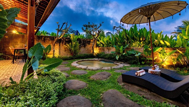Um jardim bem cuidado com área de estar, um pequeno lago e espaço para refeições.