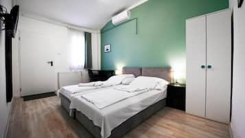 Um quarto com uma cama de casal, guarda-roupa, escrivaninha e radiador.