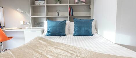 Quarto bem organizado com cama, escrivaninha e cadeira.