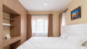 Quarto com cama, guarda-roupa de madeira e janela com cortinas.
