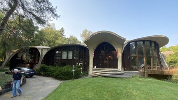 Uma casa moderna com arquitetura curvilínea única, grandes janelas e um gramado bem cuidado.