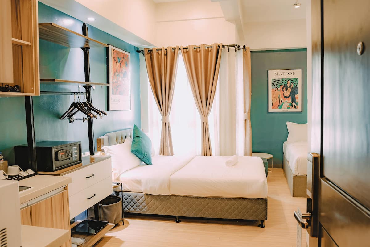 Quarto de hotel moderno com cama, mesa de cabeceira e micro-ondas.