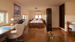 A hotel room with a bed, a desk, a chair, a wardrobe, and a large window.