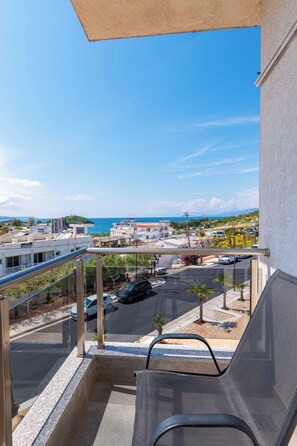 Uma varanda com vista para o mar, uma área de estacionamento e edifícios ao fundo.