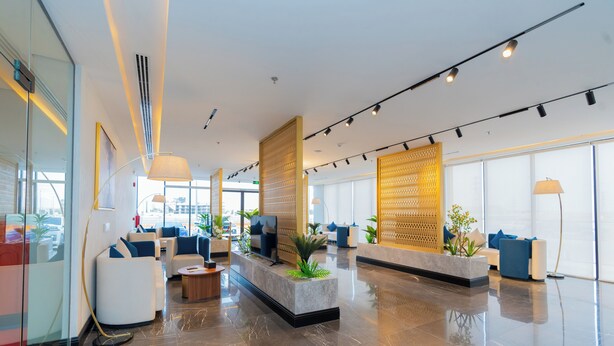 Um lobby moderno com piso de mármore, áreas de estar e grandes janelas.