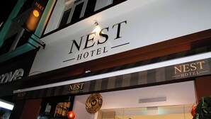 Exterior do Hotel Nest, com sua fachada exibindo o nome em destaque.