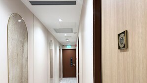 Corredor de hotel com parede de mármore, lambris de madeira e sinalização de saída.