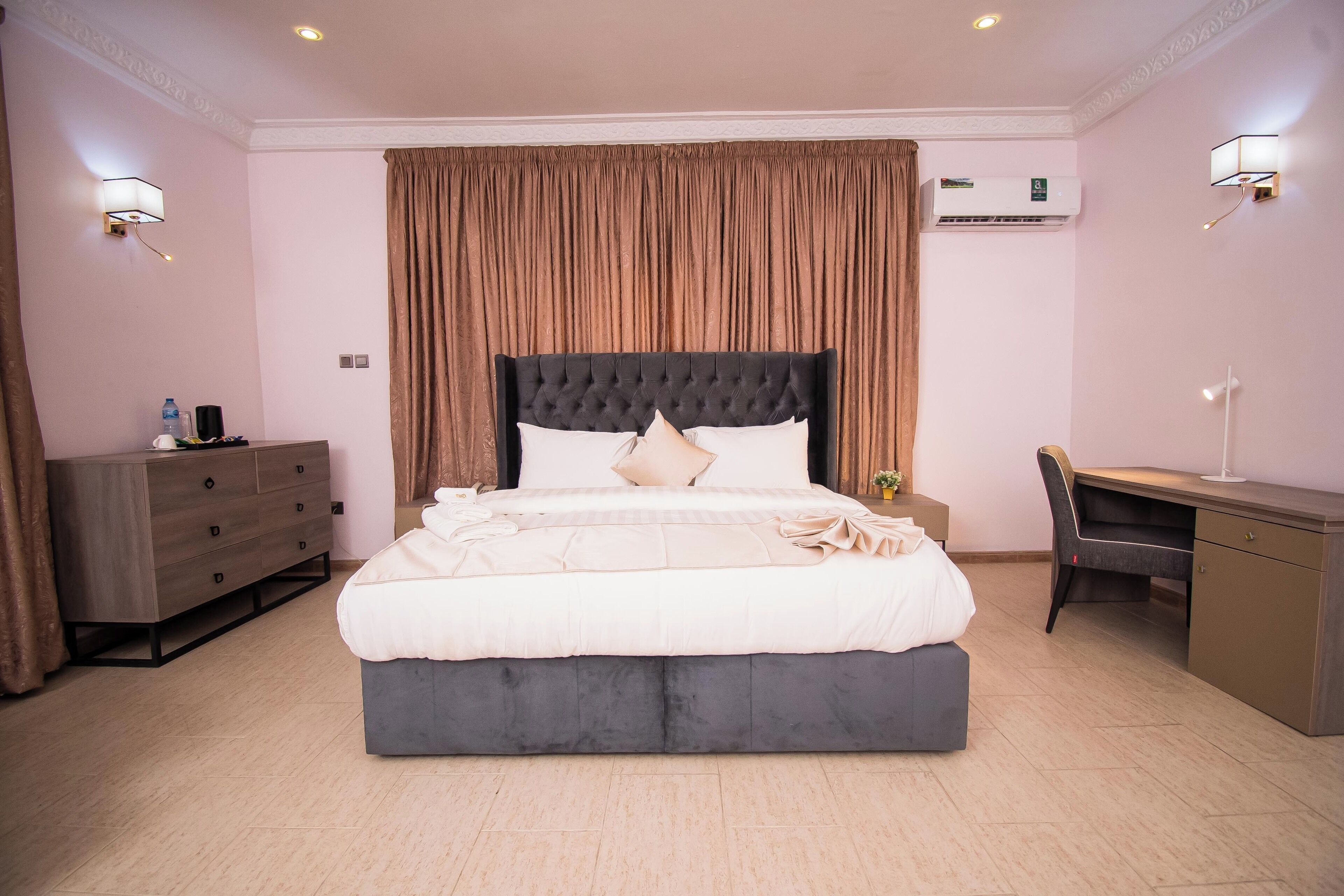 Um quarto bem arrumado com uma cama grande, uma escrivaninha e uma cadeira.