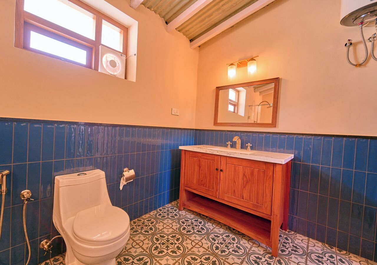 Casa de banho com sanita, toucador de madeira e espelho.