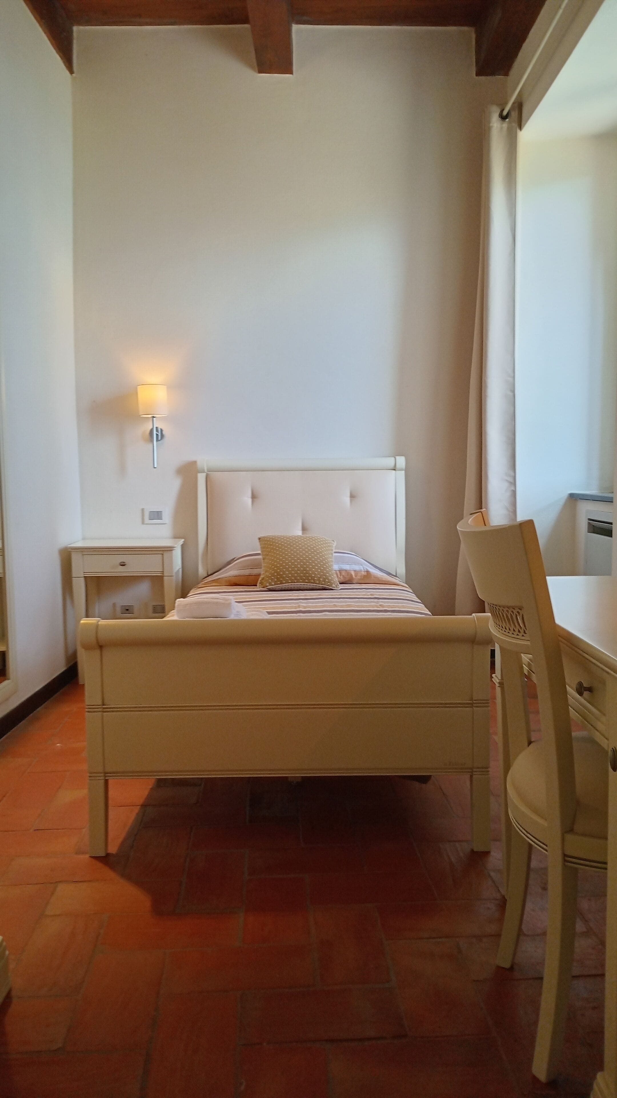 Quarto com cama, mesa de cabeceira, cadeira e abajur.