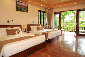 Quarto de hotel com duas camas, um quadro e uma varanda com vista para o verde.