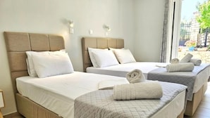 Quarto de hotel com duas camas, cada uma com cabeceira e almofadas. Há toalhas sobre as camas.