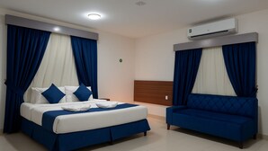 Quarto de hotel com cama, sofá e ar condicionado.