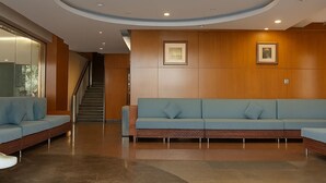 Um hall moderno com teto curvo, um sofá azul e um sofá de vime, além de uma escada.
