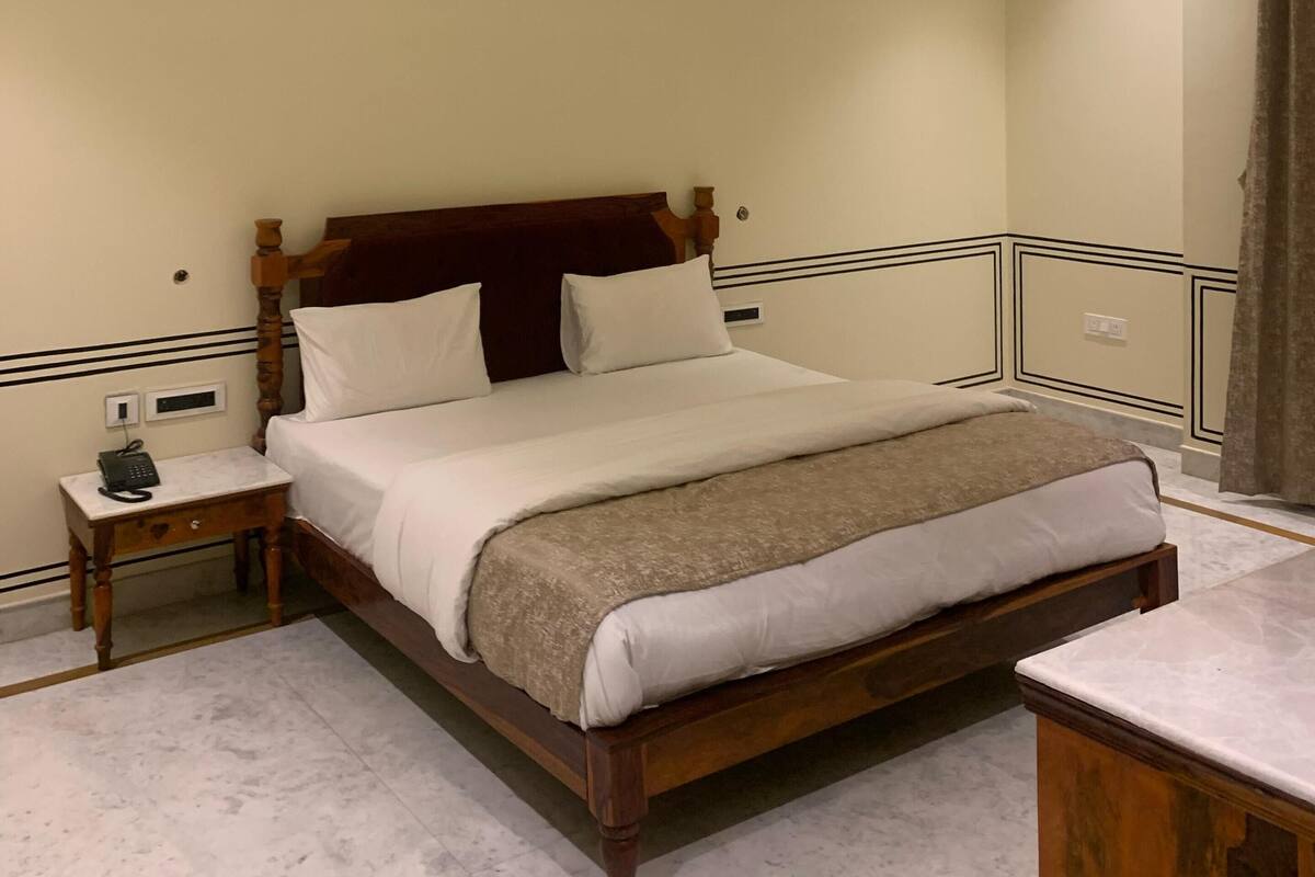 Quarto de hotel bem organizado, com uma cama grande, mesas de cabeceira, ventoinha no teto e piso de mármore.