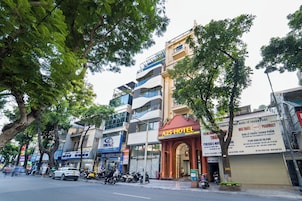 Um hotel com entrada destacada, vários andares e varandas nos andares superiores.