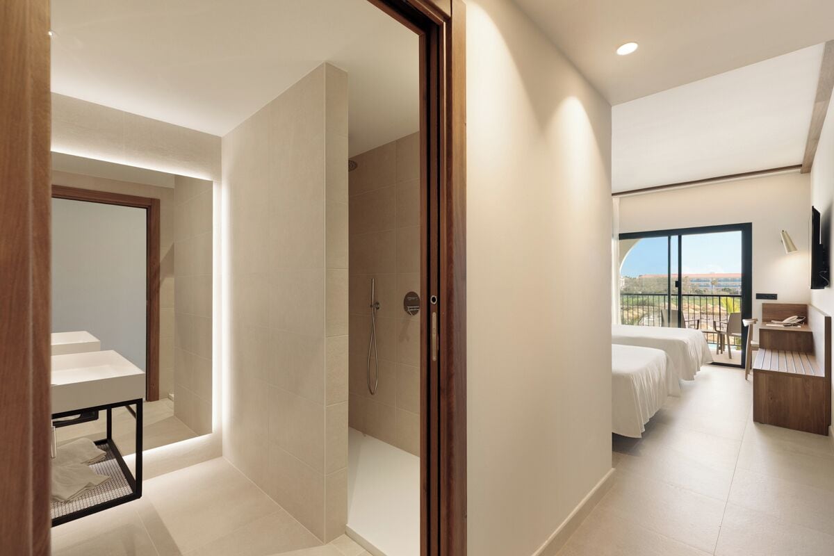 Quarto de hotel moderno com chuveiro, varanda com vista, escrivaninha e cama.