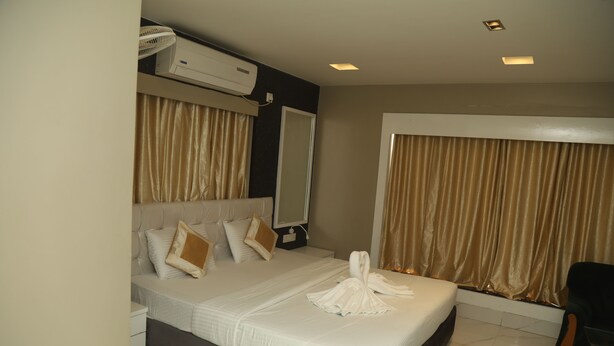 Quarto de hotel com uma cama grande, ar condicionado, espelho e cortina.