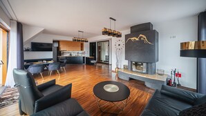 Uma sala de estar moderna com lareira, área de jantar e cozinha ao fundo.